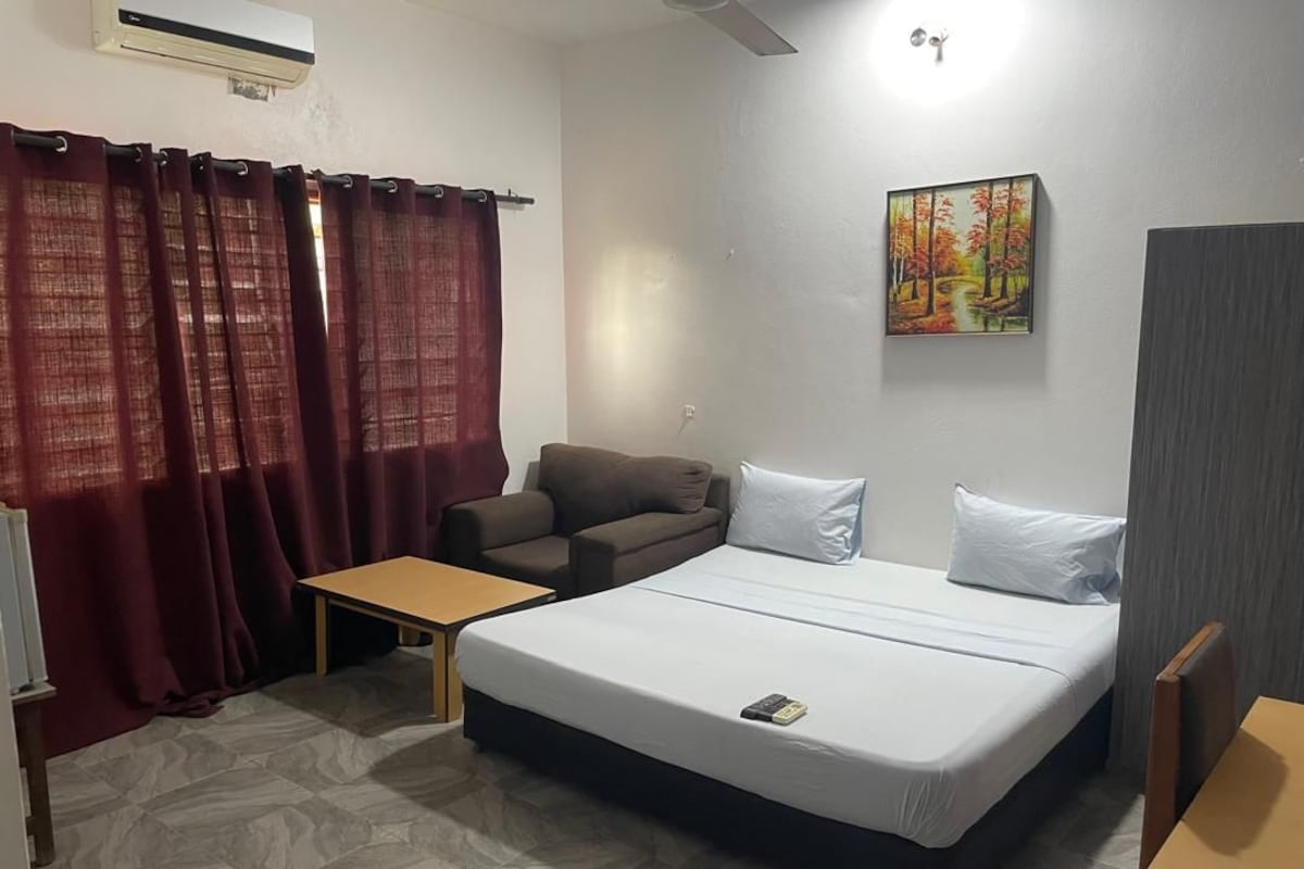Quarto de hotel com cama, sofá, mesa e um quadro na parede.
