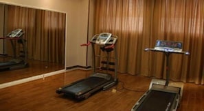 Quarto com esteira ergométrica, bicicleta fixa e espelho.
