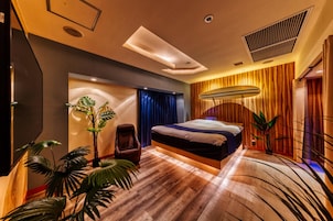 Quarto moderno com uma cama, poltrona de massagem e vários vasos de plantas.