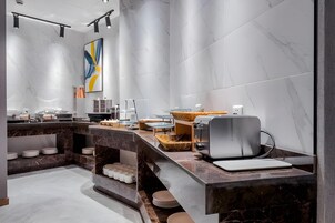 Cozinha moderna com bancadas de mármore, espaço para café e uma grande pintura abstrata na parede.