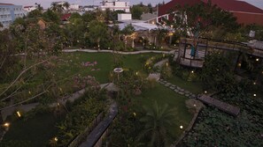 Jardim ajardinado com lago, caminhos e um deck de madeira.