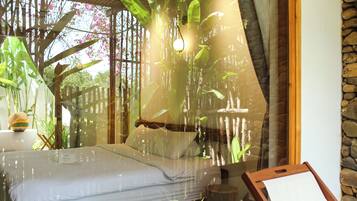 Quarto com cama, uma mesa de madeira e parede de pedra.