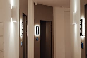 Corredor com portas, placa de número e teclado numérico.