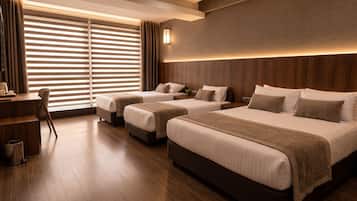 Quarto de hotel com duas camas, uma escrivaninha e uma janela grande com persianas.