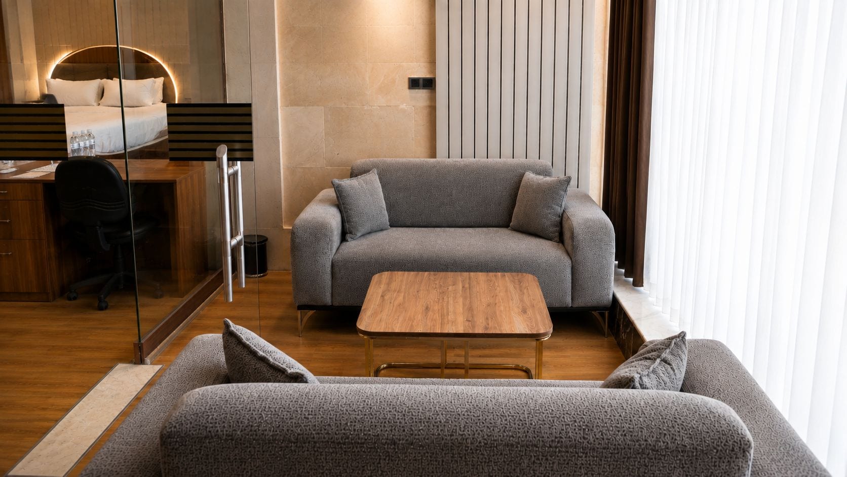 Uma sala de estar moderna com um sofá, uma mesa de centro e uma escrivaninha com uma cadeira.
