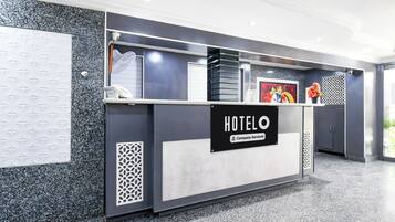 Bancada de recepção de hotel com aviso indicando serviço corporativo.