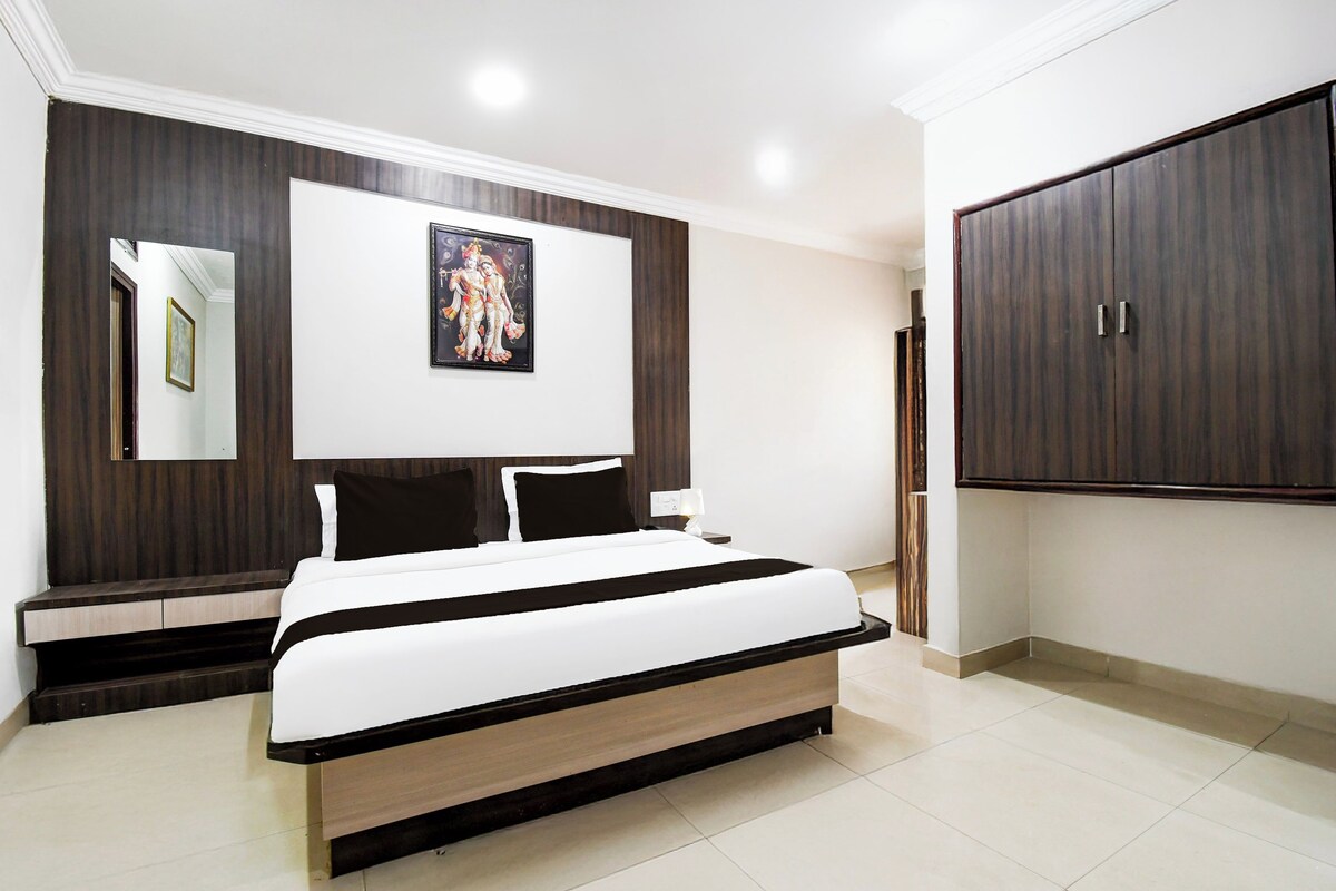 Quarto moderno com cama grande, guarda-roupa, espelho e um quadro na parede.