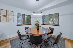 Uma sala de conferências com uma mesa redonda, seis cadeiras e amplas janelas com vista para a floresta.