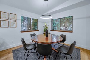 Uma sala de conferências com uma mesa redonda, seis cadeiras e amplas janelas com vista para a floresta.