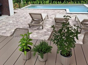 Área de estar ao ar livre com piscina ao fundo.