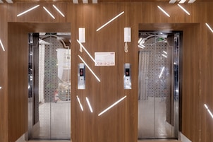 Interior de elevador com painéis de madeira e luminárias modernas.
