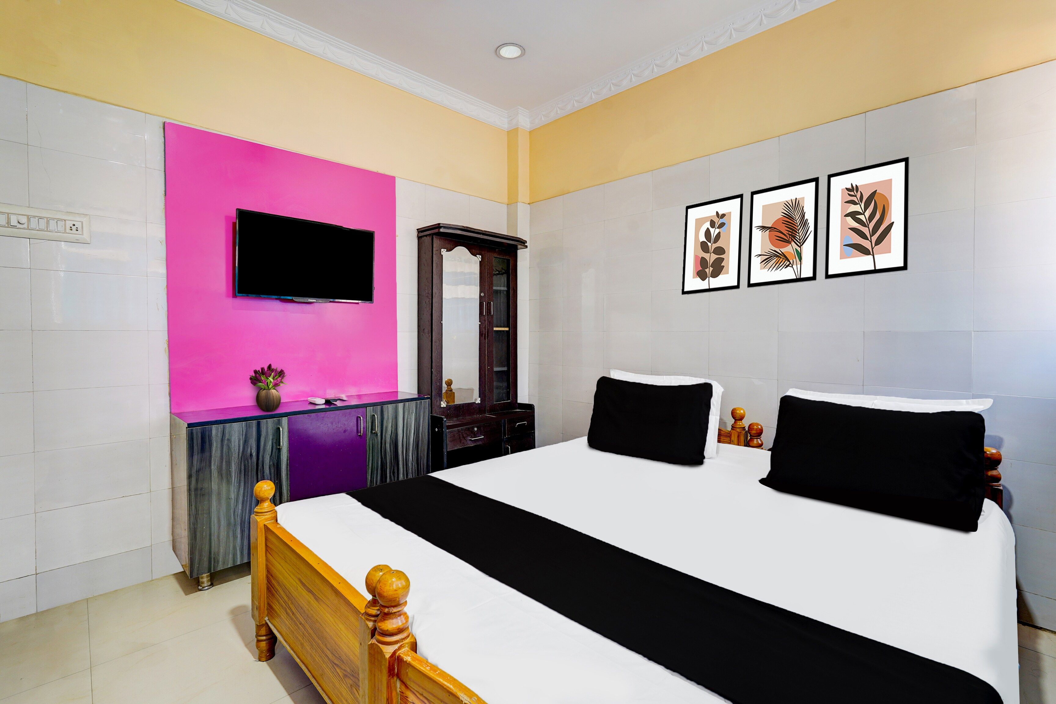 Quarto com cama, televisão, cômoda e espelho.