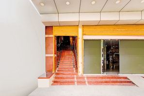 Escada que leva a uma entrada de loja com persiana amarela e porta de vidro.