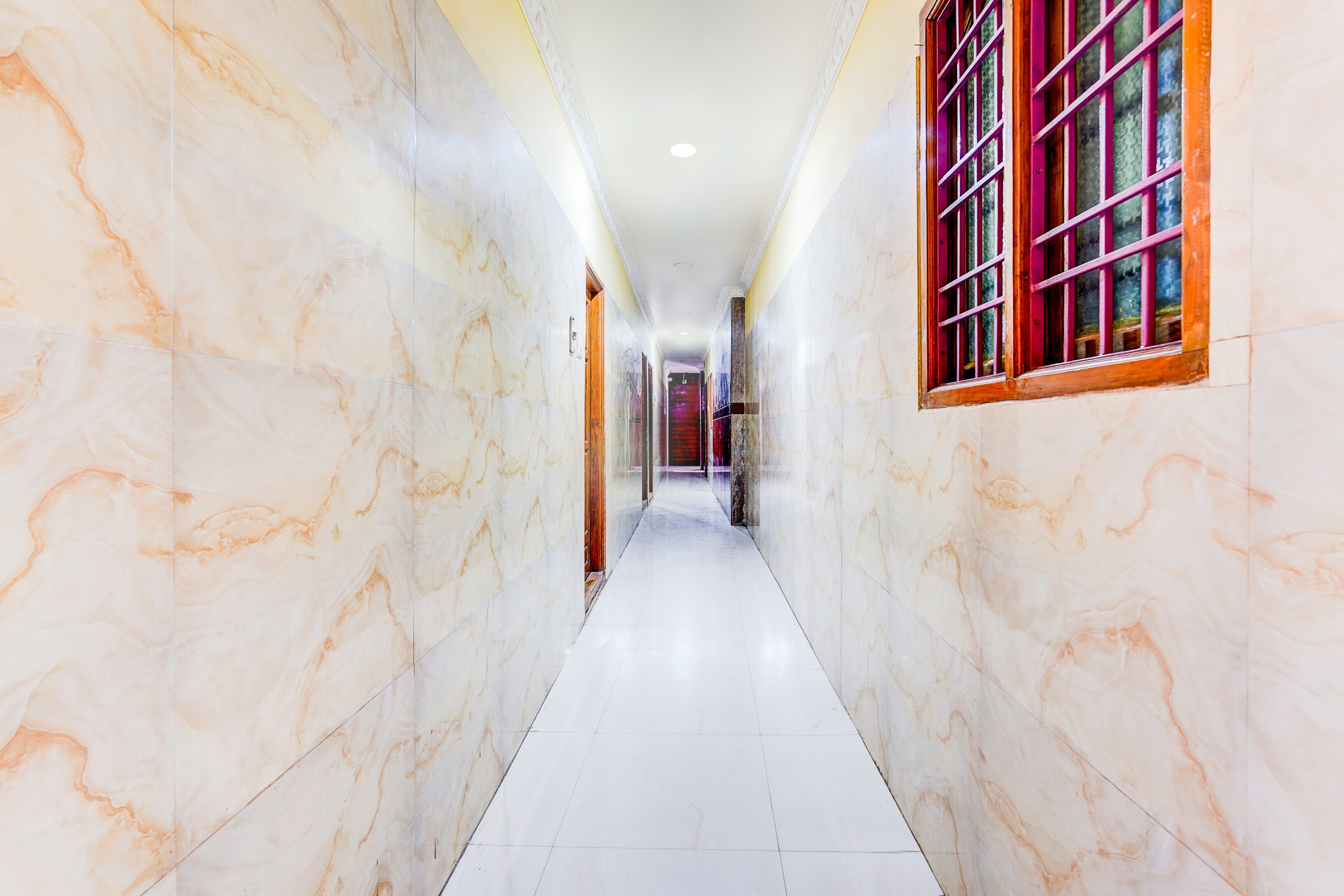 Um corredor de mármore com uma porta de vidro no final.