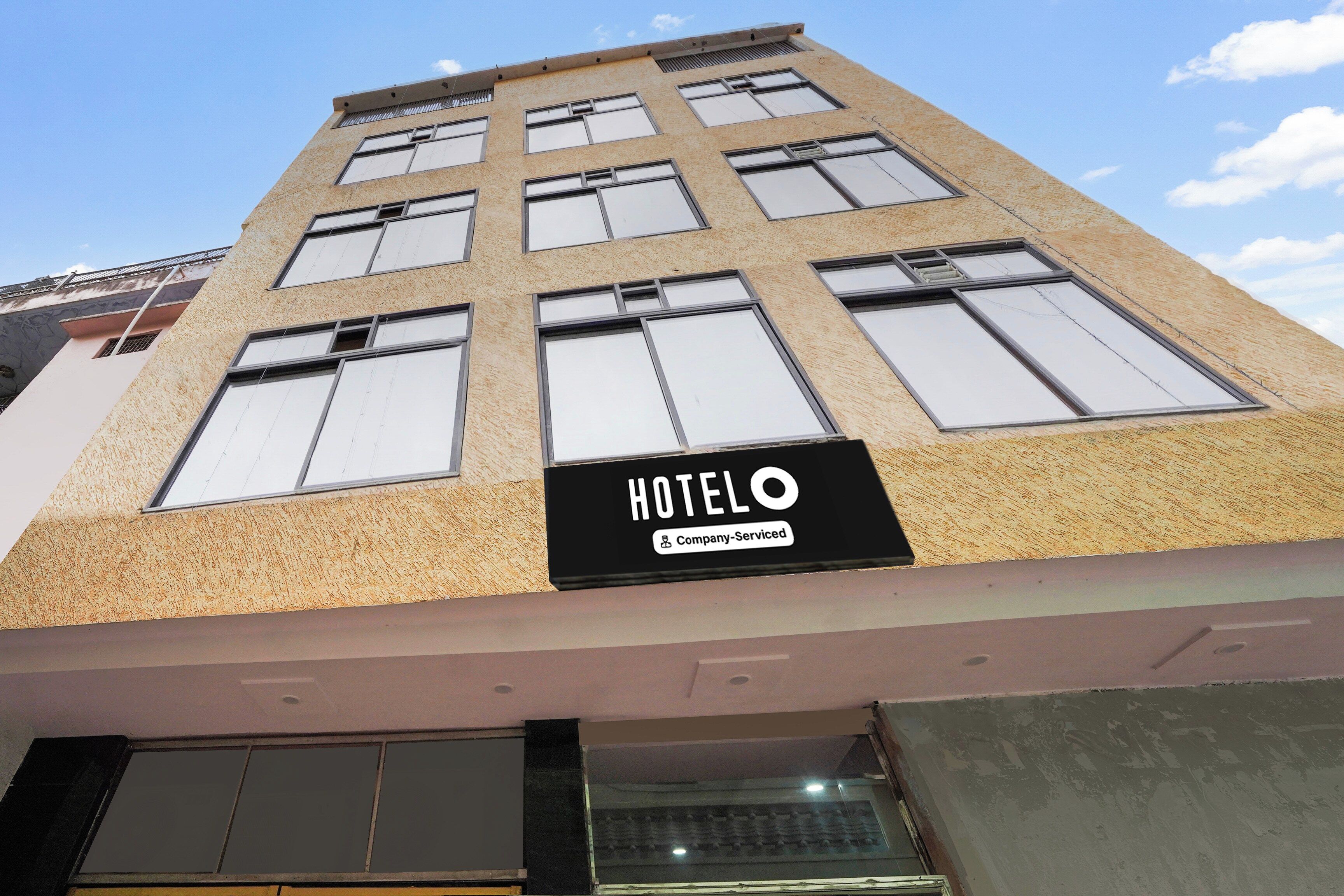 Um edifício com várias janelas e uma placa com a inscrição 'HOTEL Company-Serviced'.