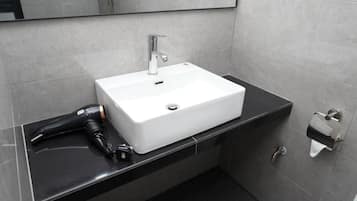 Casa de banho moderna com lavatório branco, bancada preta e espelho acima.