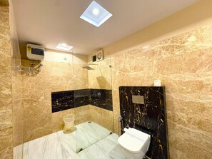 Uma casa de banho moderna com cabine de duche em vidro, sanita e lavatório de mármore.