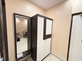 Quarto com guarda-roupa, espelho e cadeira.