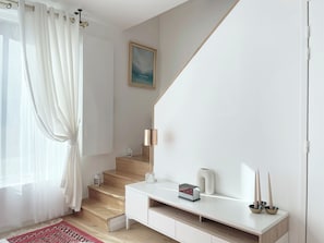 Um interior moderno com escada, mesa de console branca e pintura na parede.
