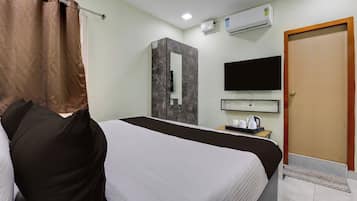 Quarto de hotel com cama, televisão, ar condicionado, espelho e porta.