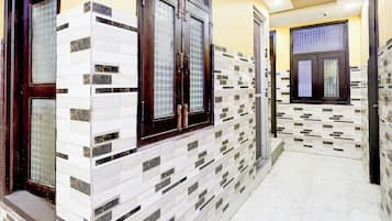 Um corredor com paredes e portas estampadas, que leva a um quarto com piso de azulejos.