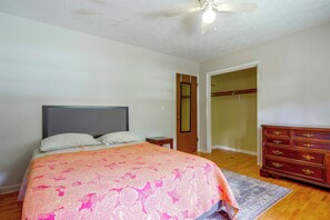 Quarto com cama, cômoda, ventoinha no teto e porta para um armário.