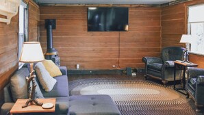 Um quarto aconchegante com lareira, um sofá, uma poltrona e um abajur.