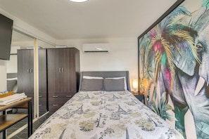 Quarto de hotel com cama, guarda-roupa e uma grande pintura na parede.