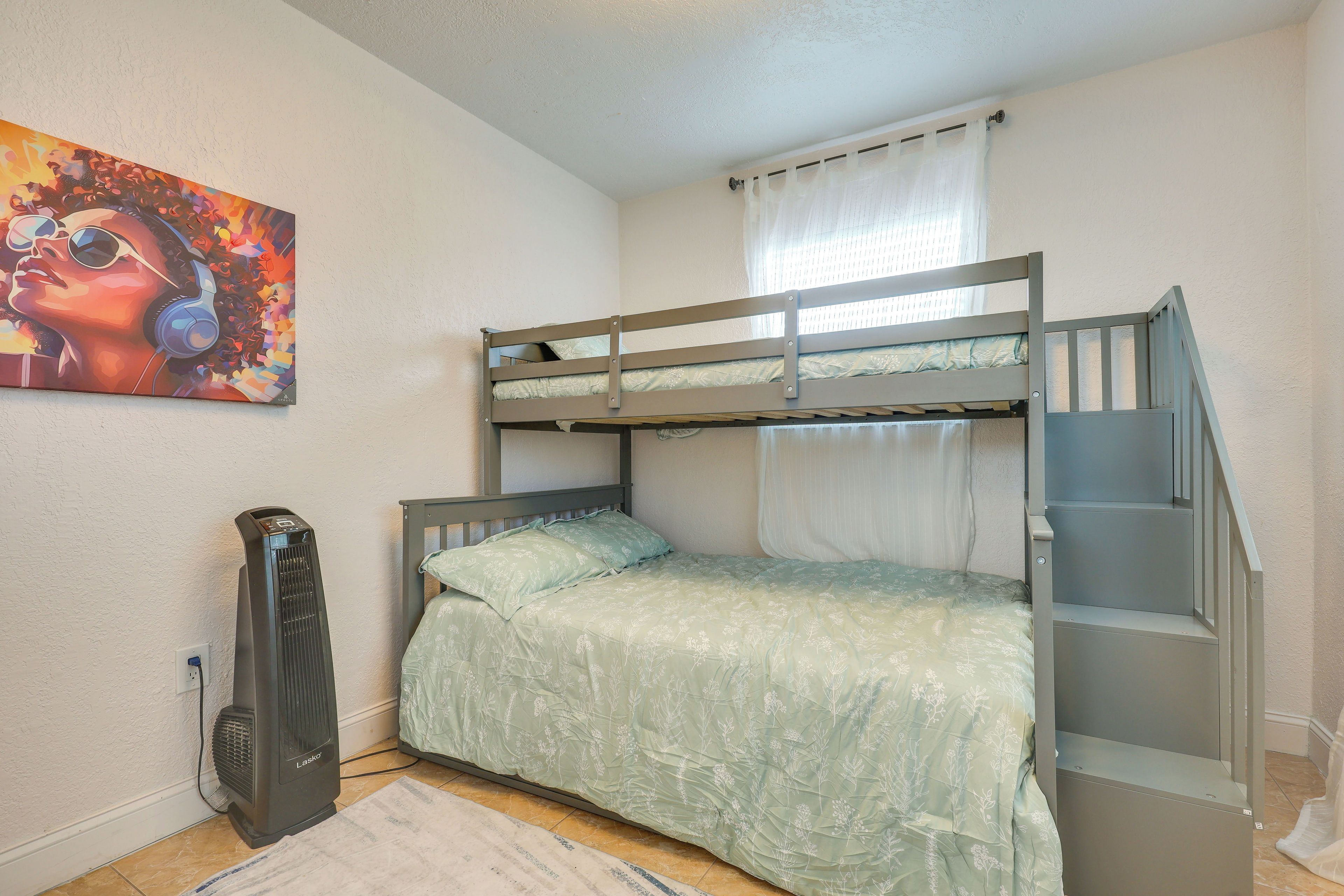 Uma cama beliche com escada, um radiador e um quadro na parede.