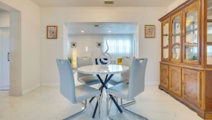 Uma sala de jantar com uma mesa redonda, quatro cadeiras e um armário de madeira.