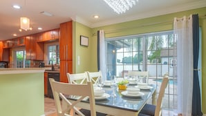 Cozinha moderna com armários de madeira e área de jantar com mesa e cadeiras de vidro.