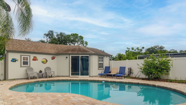 Um imóvel residencial com piscina, móveis de varanda e deck revestido com azulejos.