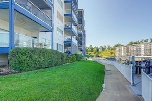 Um edifício de apartamentos moderno com varandas, um gramado bem cuidado e uma área de cais com barcos.