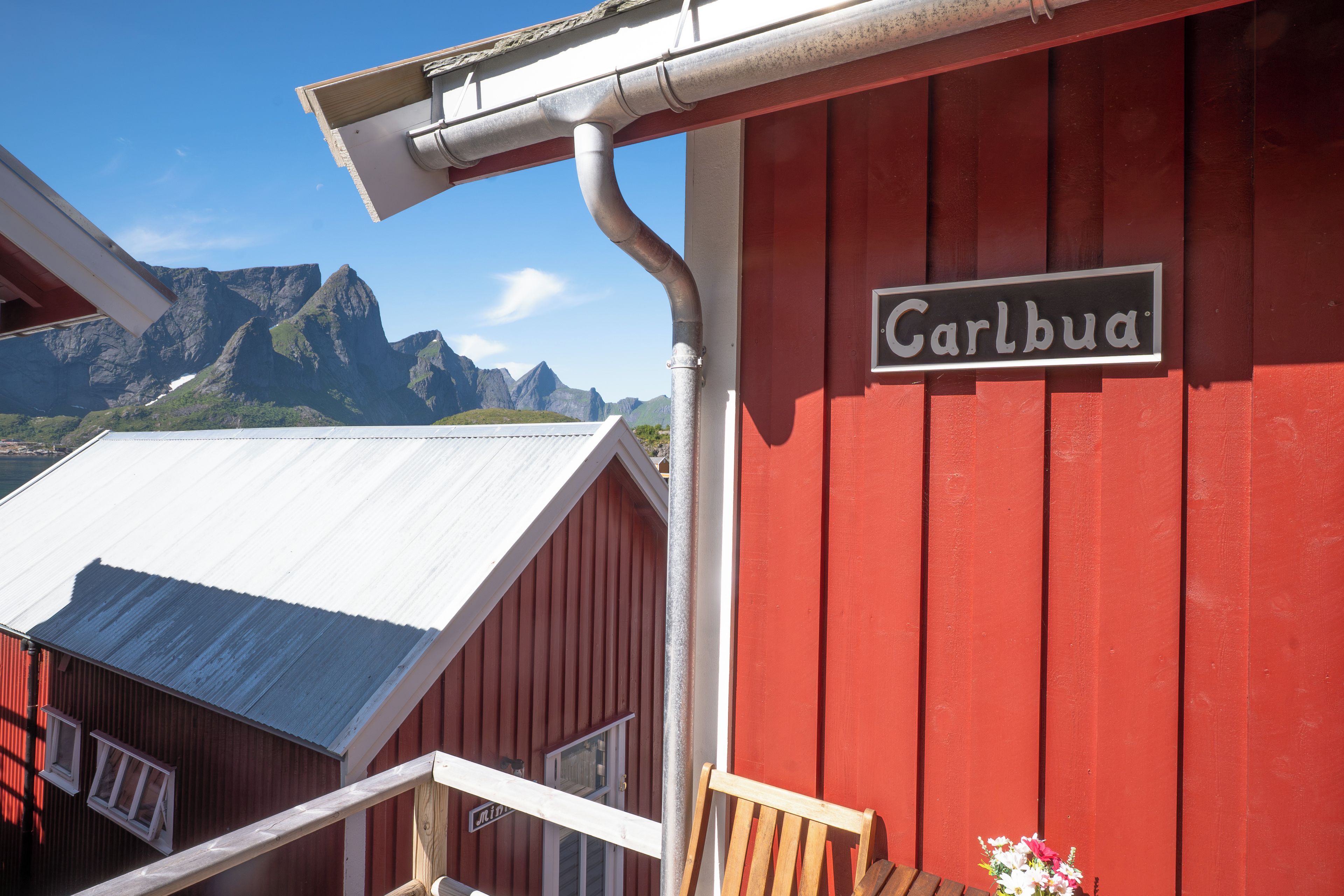 Um edifício vermelho com uma placa que diz 'Carlbua' e vista para montanhas ao fundo.