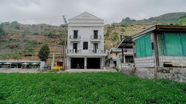 Um edifício de dois andares com entrada central e varanda no andar superior.