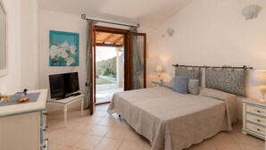 Quarto com cama, mesas de cabeceira, televisão e vista para o exterior.