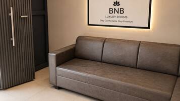 Um interior moderno com um sofá de couro, uma placa emoldurada acima e uma porta com linhas verticais.