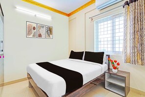 Quarto moderno com cama, mesa de cabeceira, janela com cortinas e obras de arte nas paredes.
