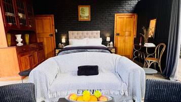 Quarto com cama, lustre, mesa de jantar com frutas e móveis de vime.