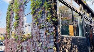 Um edifício com fachada de tijolos, parcialmente coberto por plantas trepadeiras.