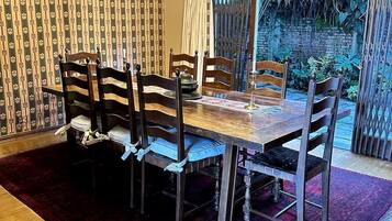 Uma sala de jantar com mesa e cadeiras de madeira, um lustre e papel de parede estampado.
