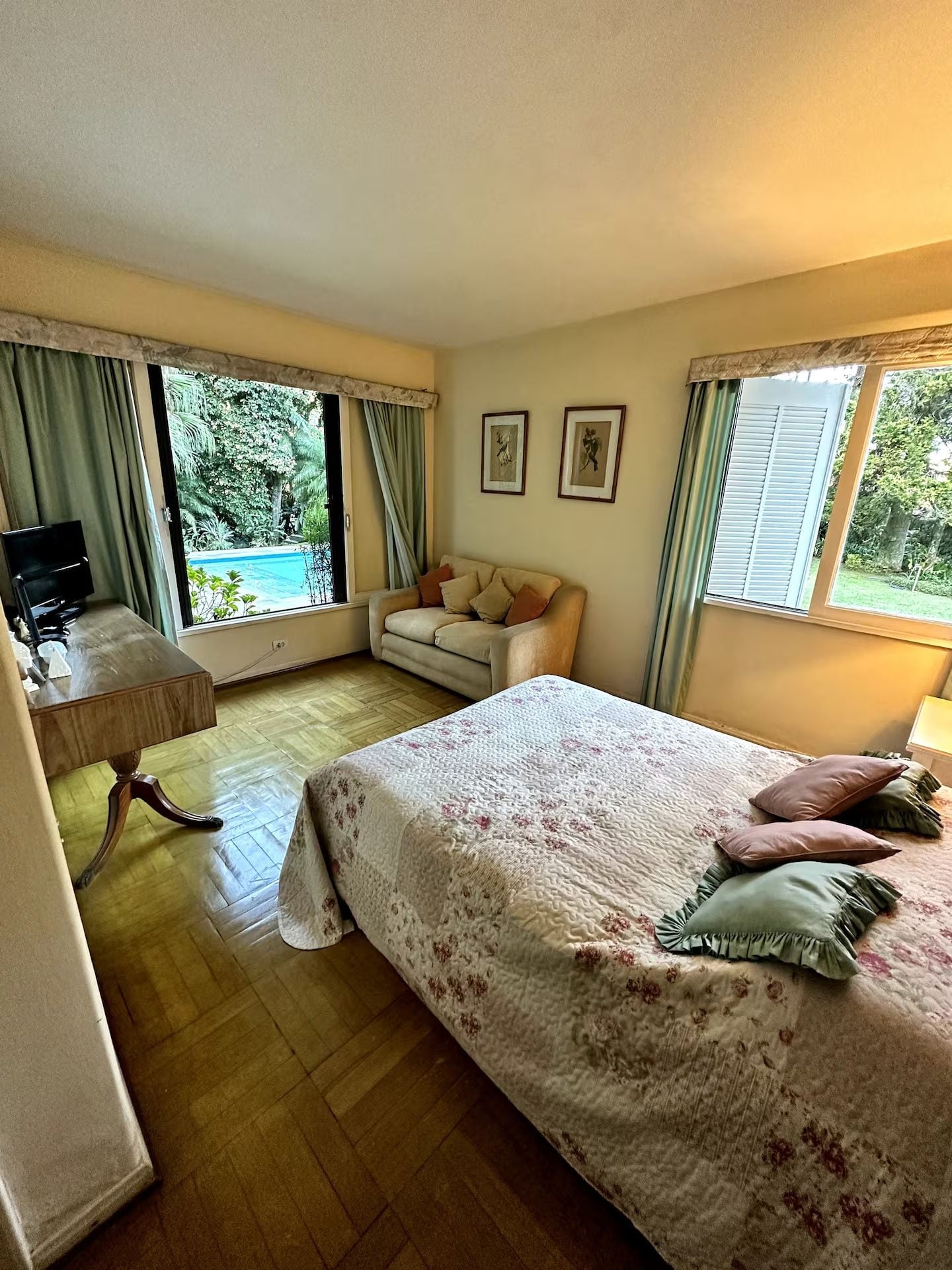 Um quarto com cama, sofá, escrivaninha e televisão.