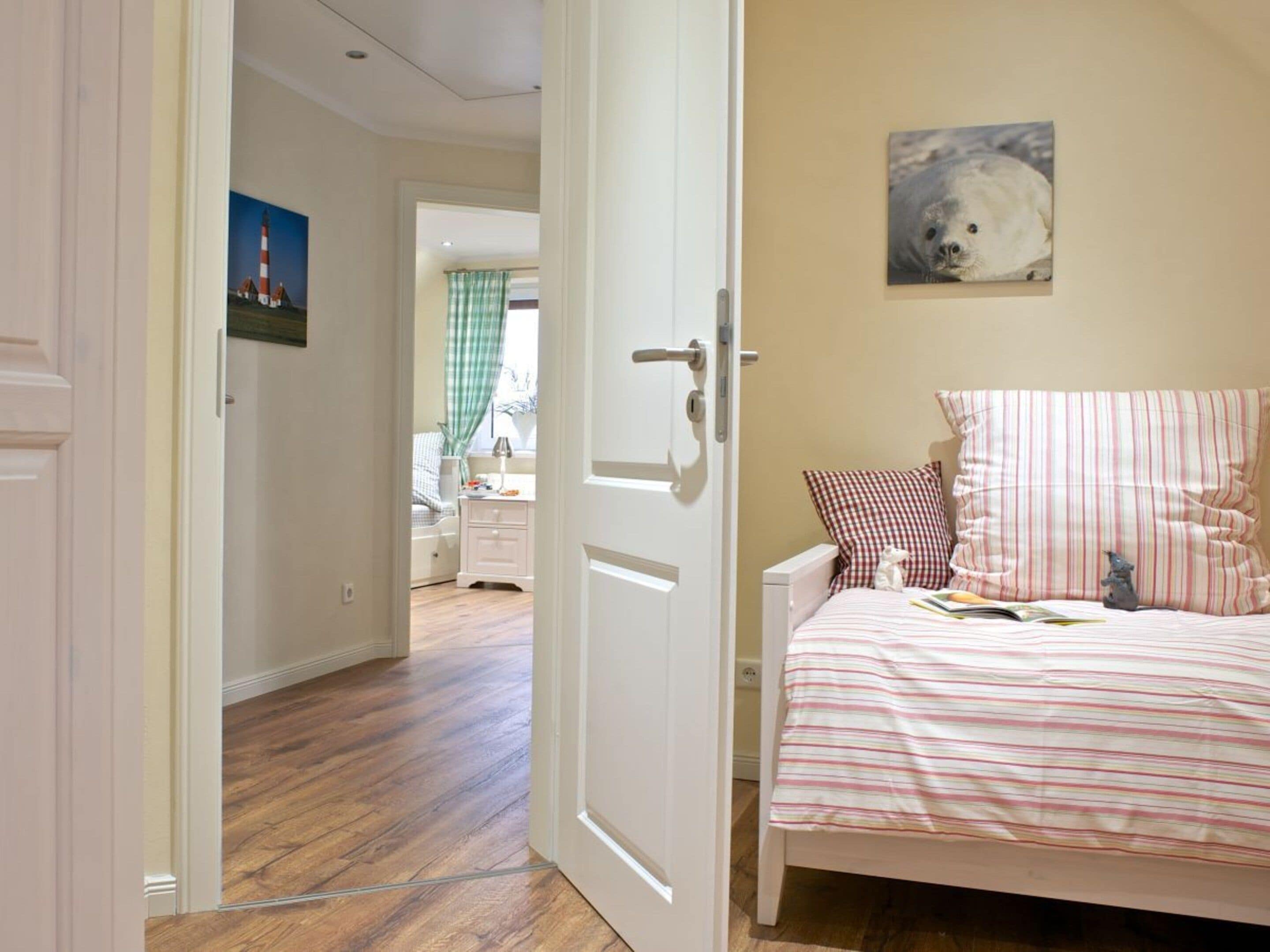 Quarto com cama, pintura e vista para outro cômodo.