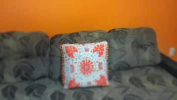 Sofá com almofada estampada em frente a parede laranja.