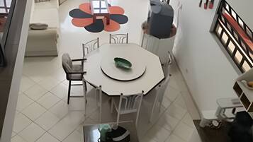 Uma sala de estar moderna com um sofá, uma mesa de jantar com cadeiras e uma área de cozinha com fogão.