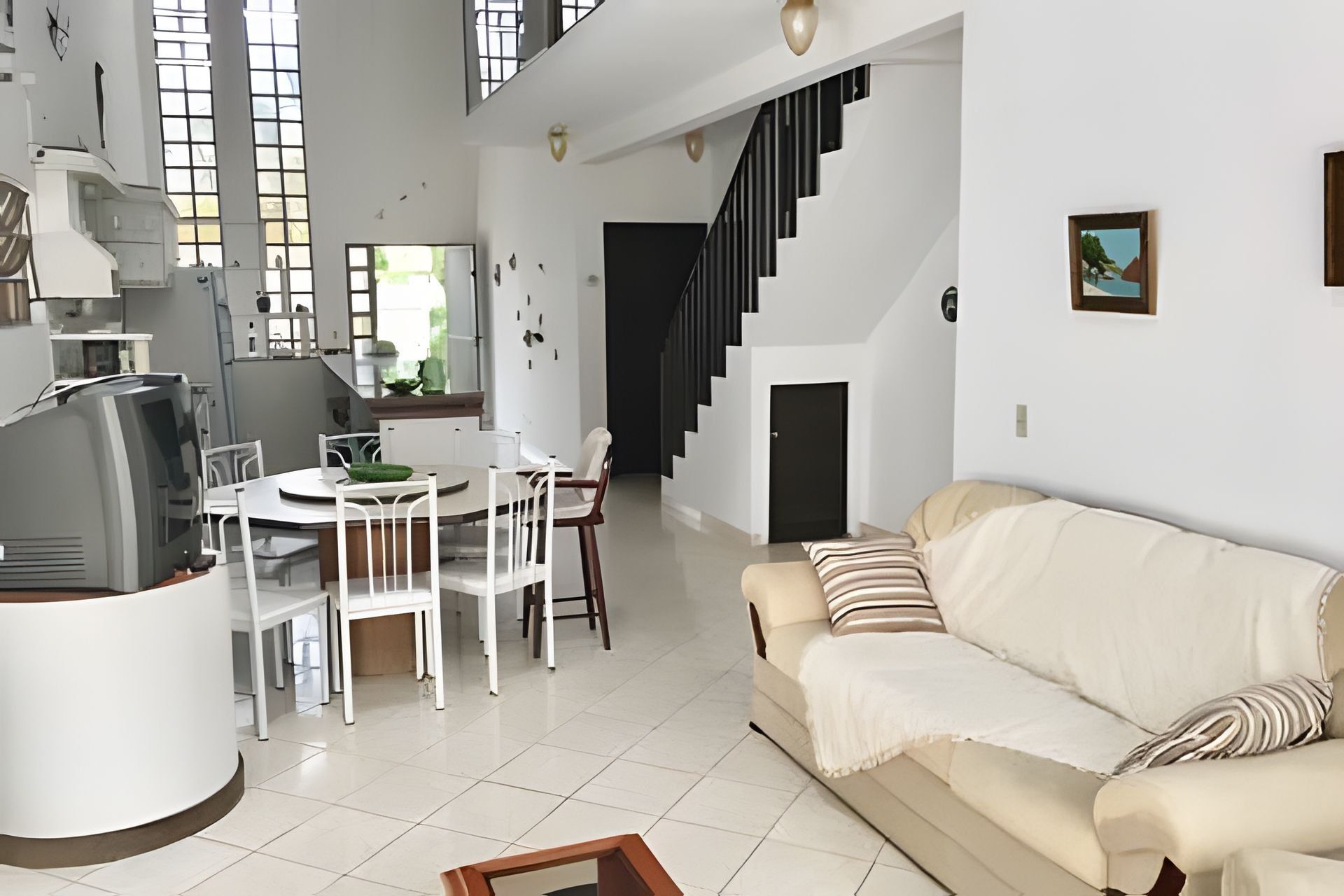 Um espaço de estar moderno com área de jantar, sofá e escada.