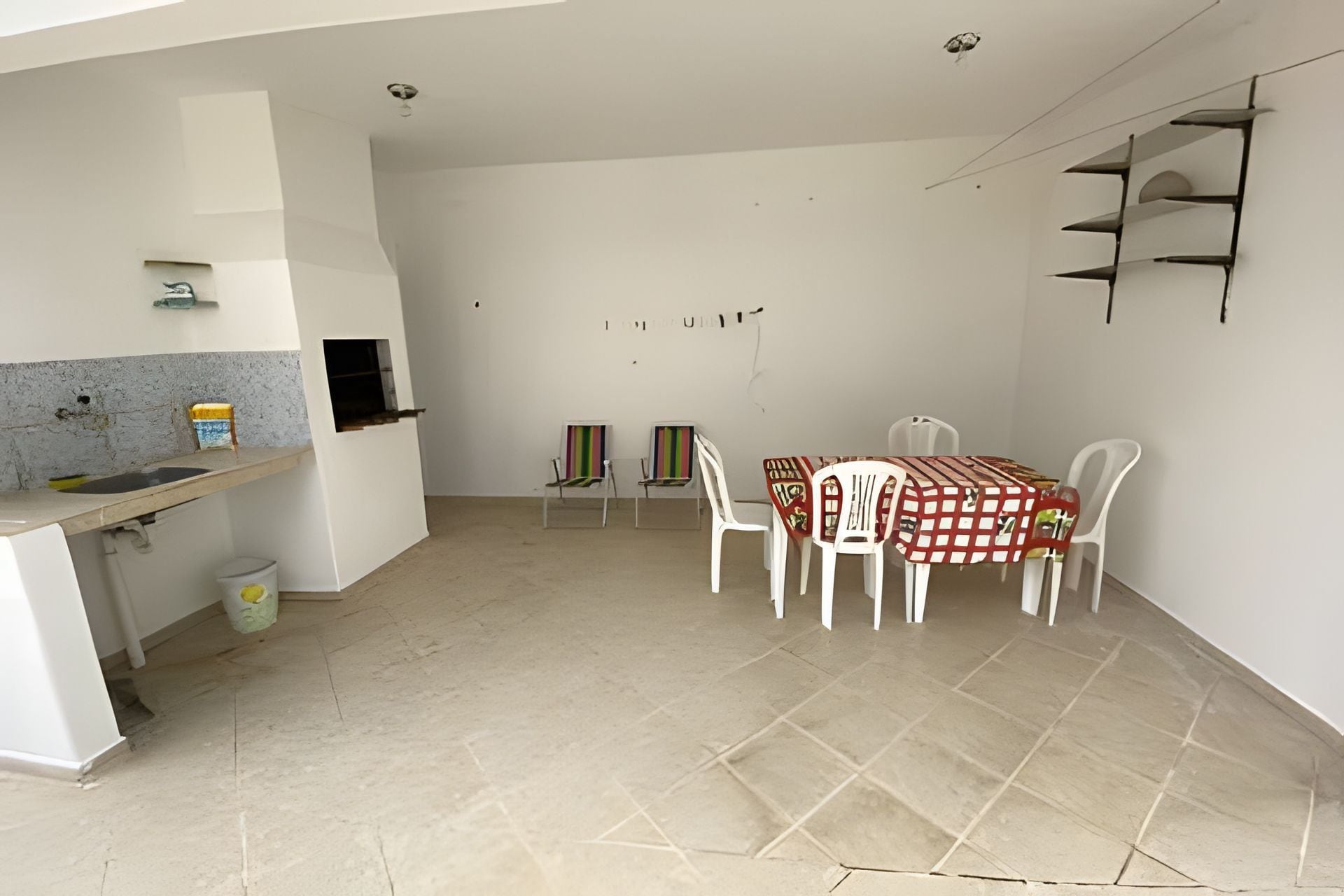 Cozinha com bancada, pia e uma pequena janela. Há uma área de refeições com mesa e cadeiras.