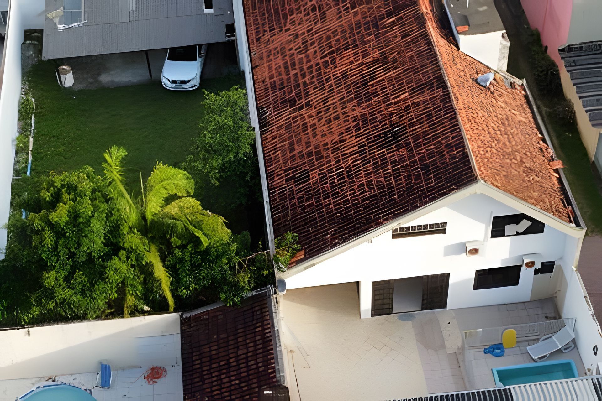 Um imóvel residencial com piscina, garagem e telhado de telhas vermelhas.