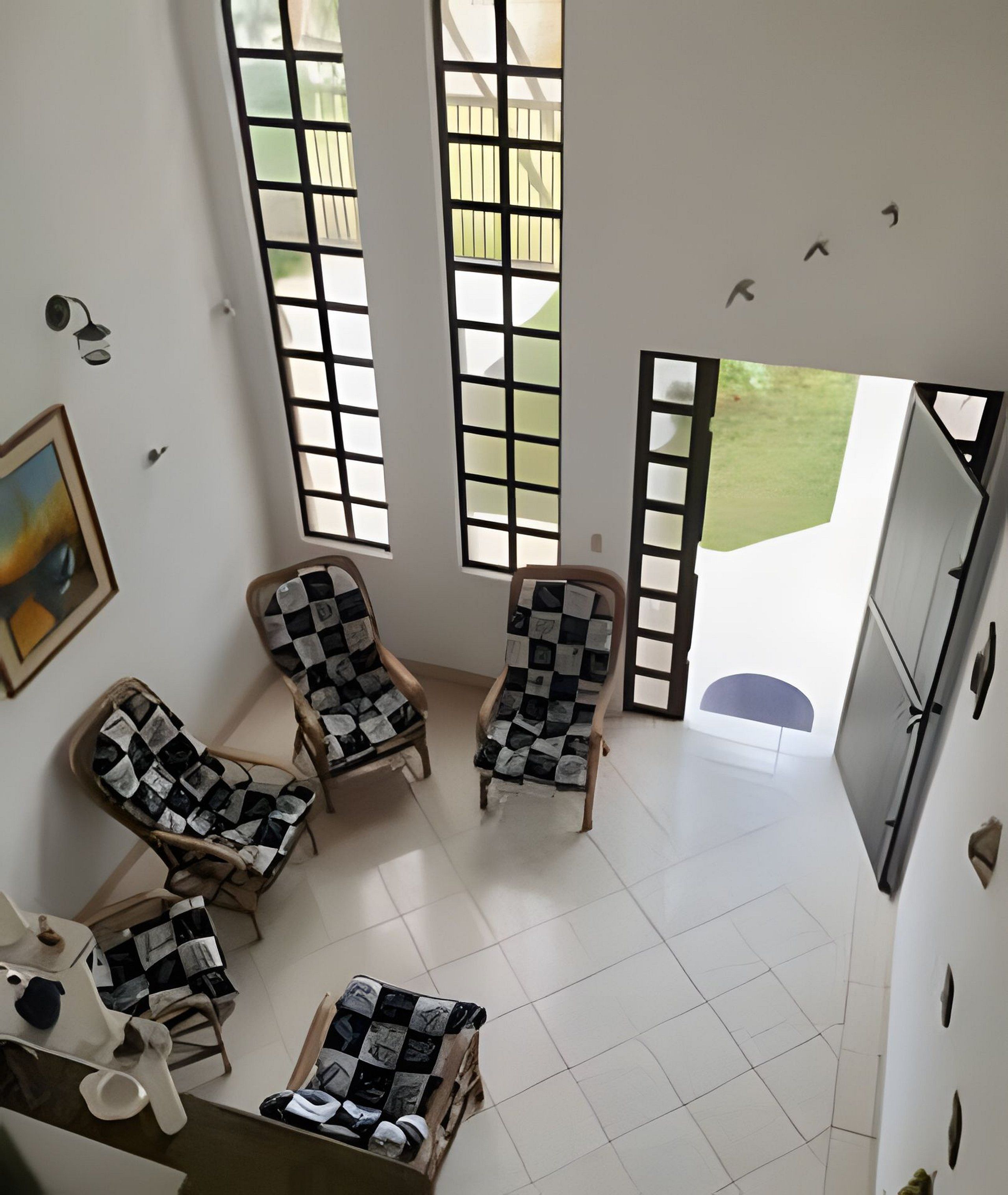 Um quarto com duas poltronas xadrez, uma mesa pequena e um quadro na parede.