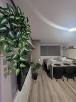 Quarto moderno com cama, escrivaninha e uma grande planta em vaso.